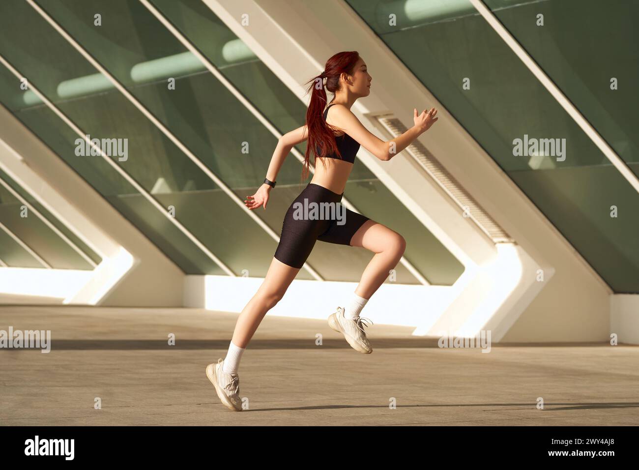 Active woman athlete is jogging on morning on modern building ...