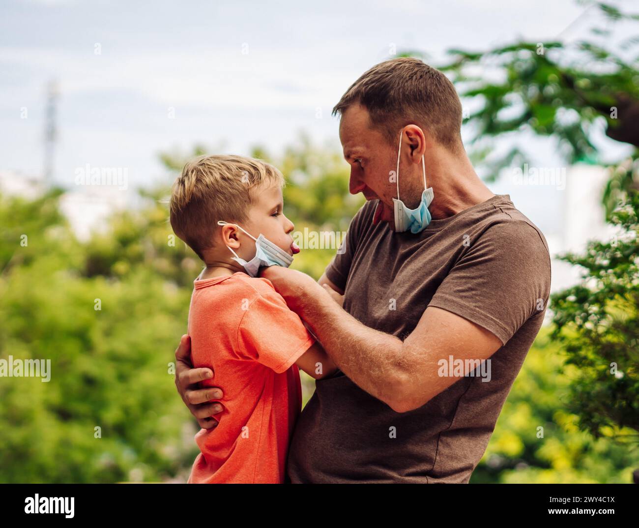 Father and little son hugging, making faces, show a tongue, open mouth ...