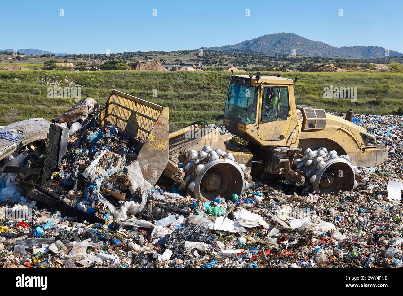 Heavy machinery shredding garbage in an open air landfill. Waste Stock ...