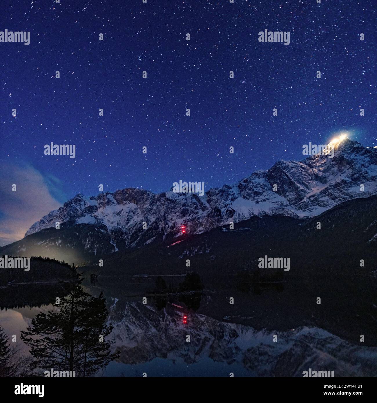 a snow-covered mountain range at night with the starry sky above and the reflection over the ...