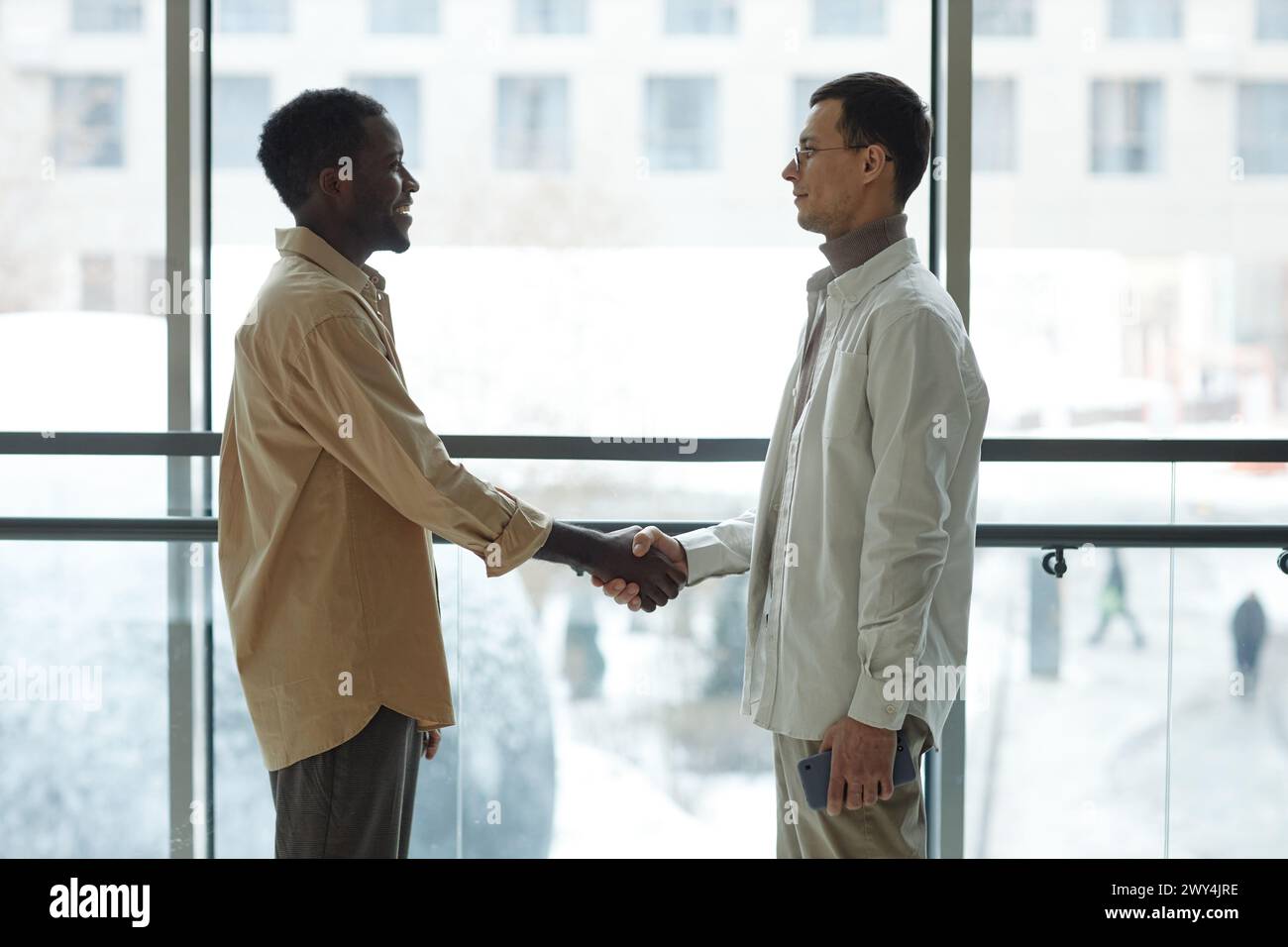 Side view portrait of two stylish young men Black and Caucasian shaking ...