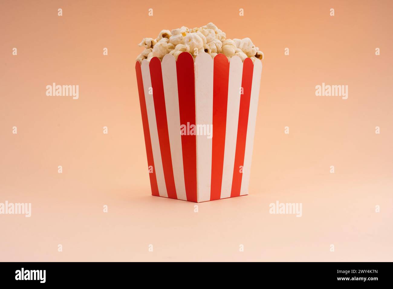A striped popcorn bucket on a tan background Stock Photo - Alamy