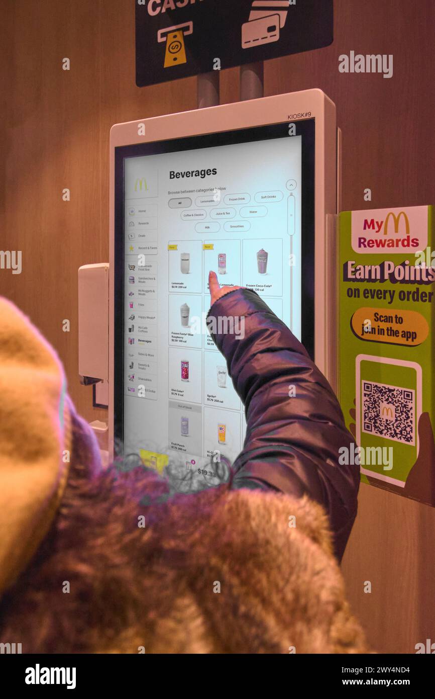 Customer in fast food restaurant using a digital self-service kiosk to ...