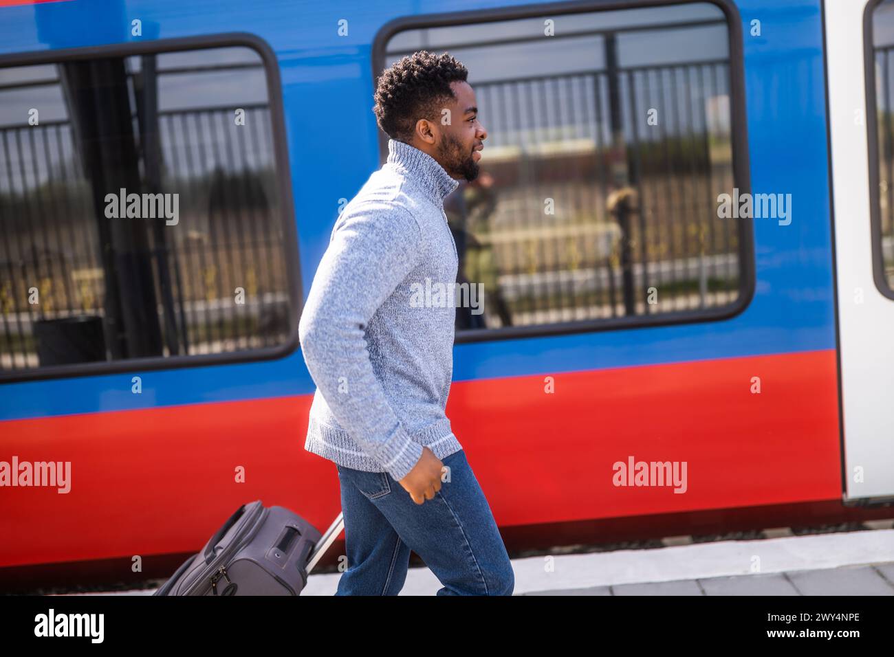 Man running to a leaving train along railway station with suitcase ...