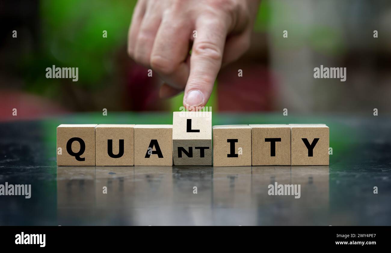 Hand turns wooden cube and changes the word quantity to quality Stock ...