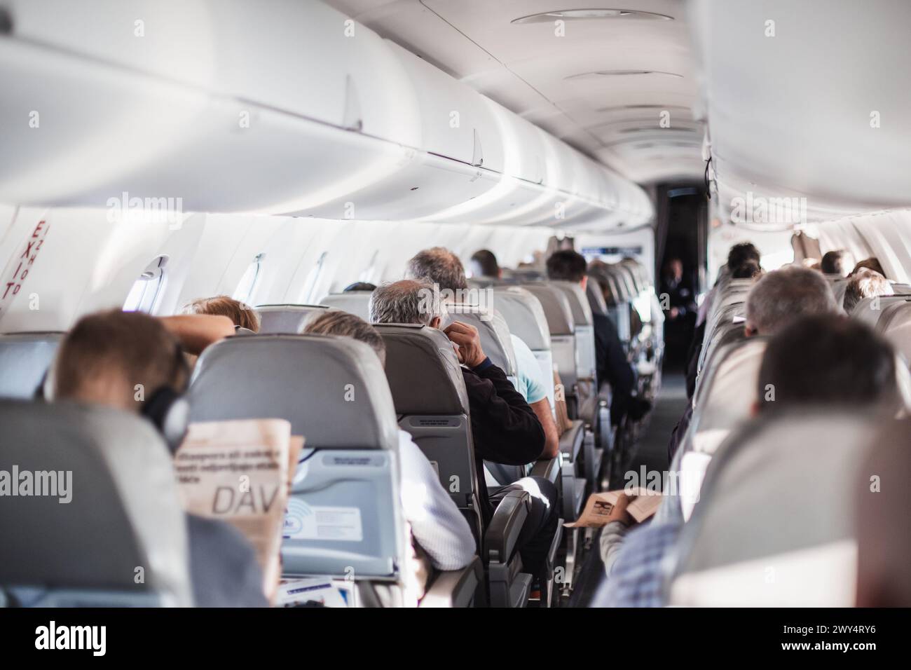 Interior of airplane with passengers on seats and stewardess in uniform ...