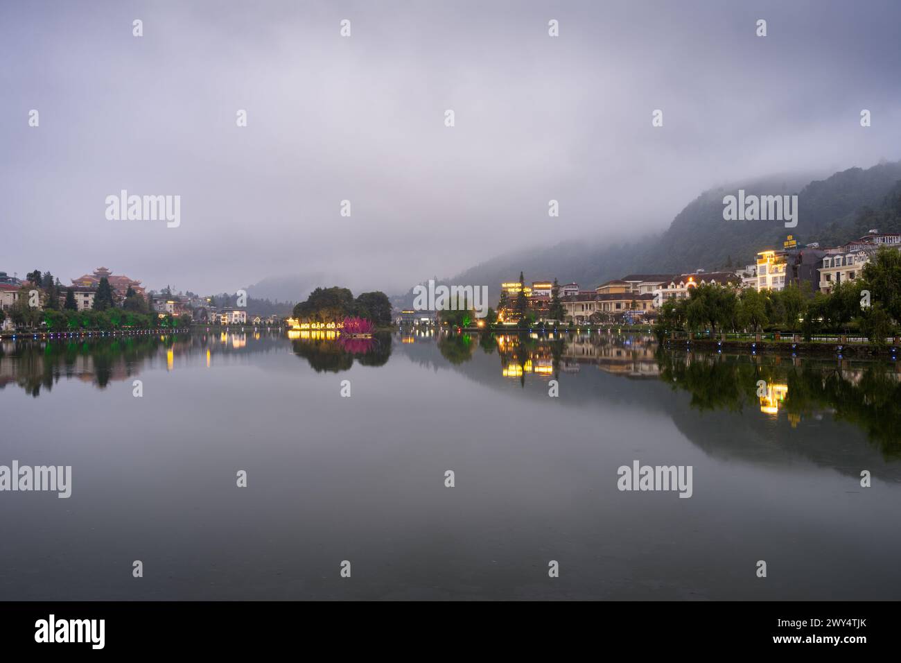 A scenic view of Sa Pa Lake in Vietnam enveloped in mist, with glowing ...