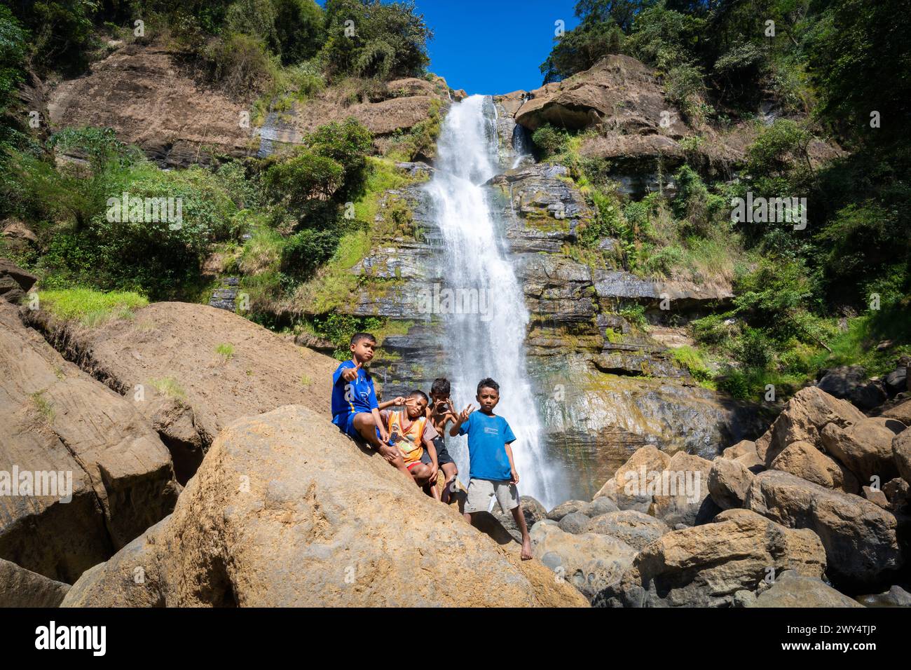 A group of local kids standing in front of a tropical rainforest ...