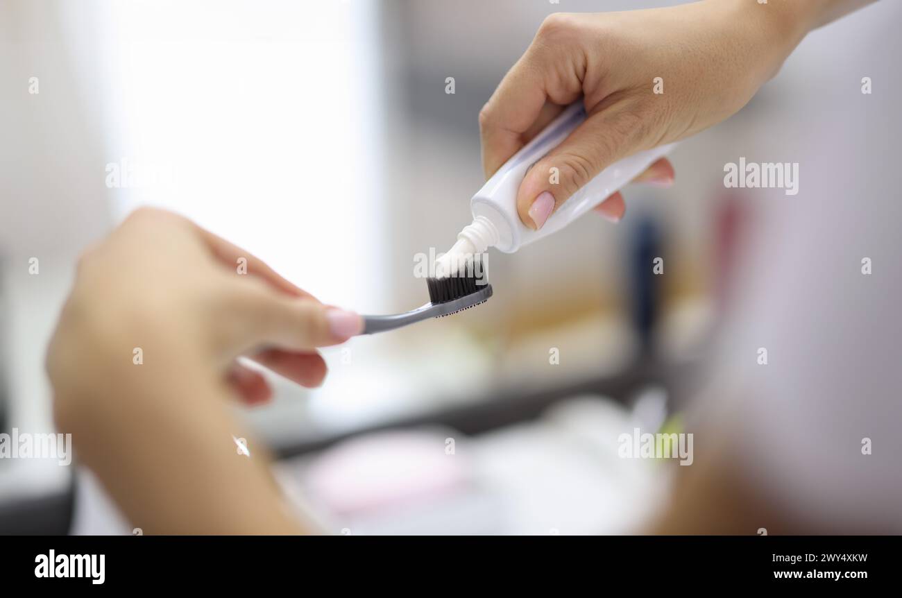 Female hand squeezing toothpaste from tube onto toothbrush close-up ...