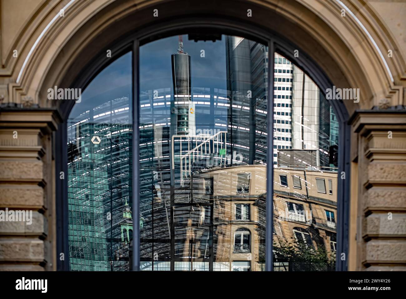 Reflection of a glass building in an arched doorway of a large building ...