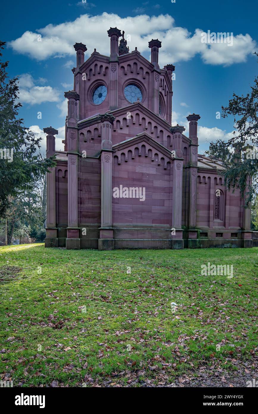Ancient red stone church on lush green lawn beside trees Stock Photo ...