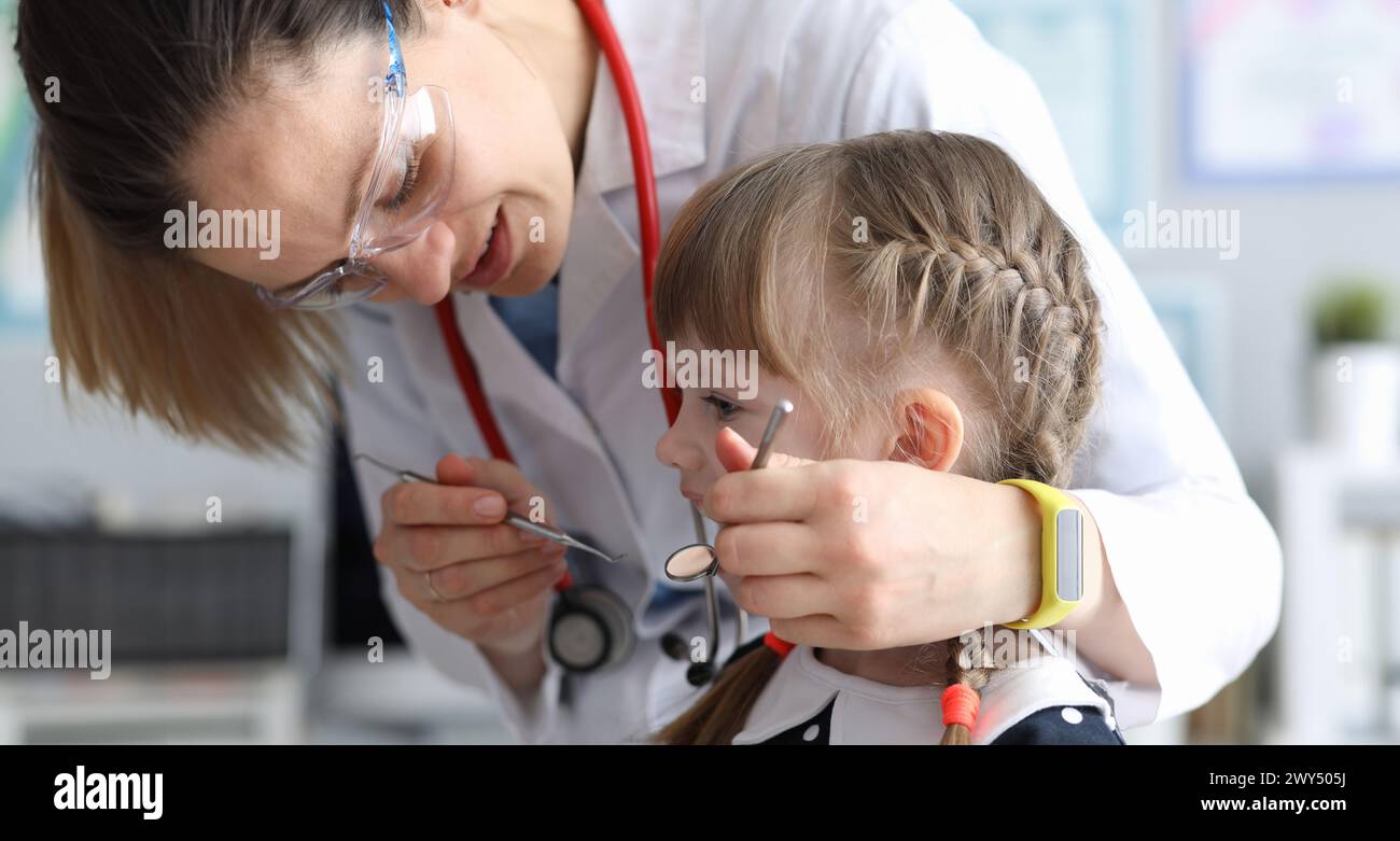 Pediatric dentist examines teeth little girl Stock Photo - Alamy