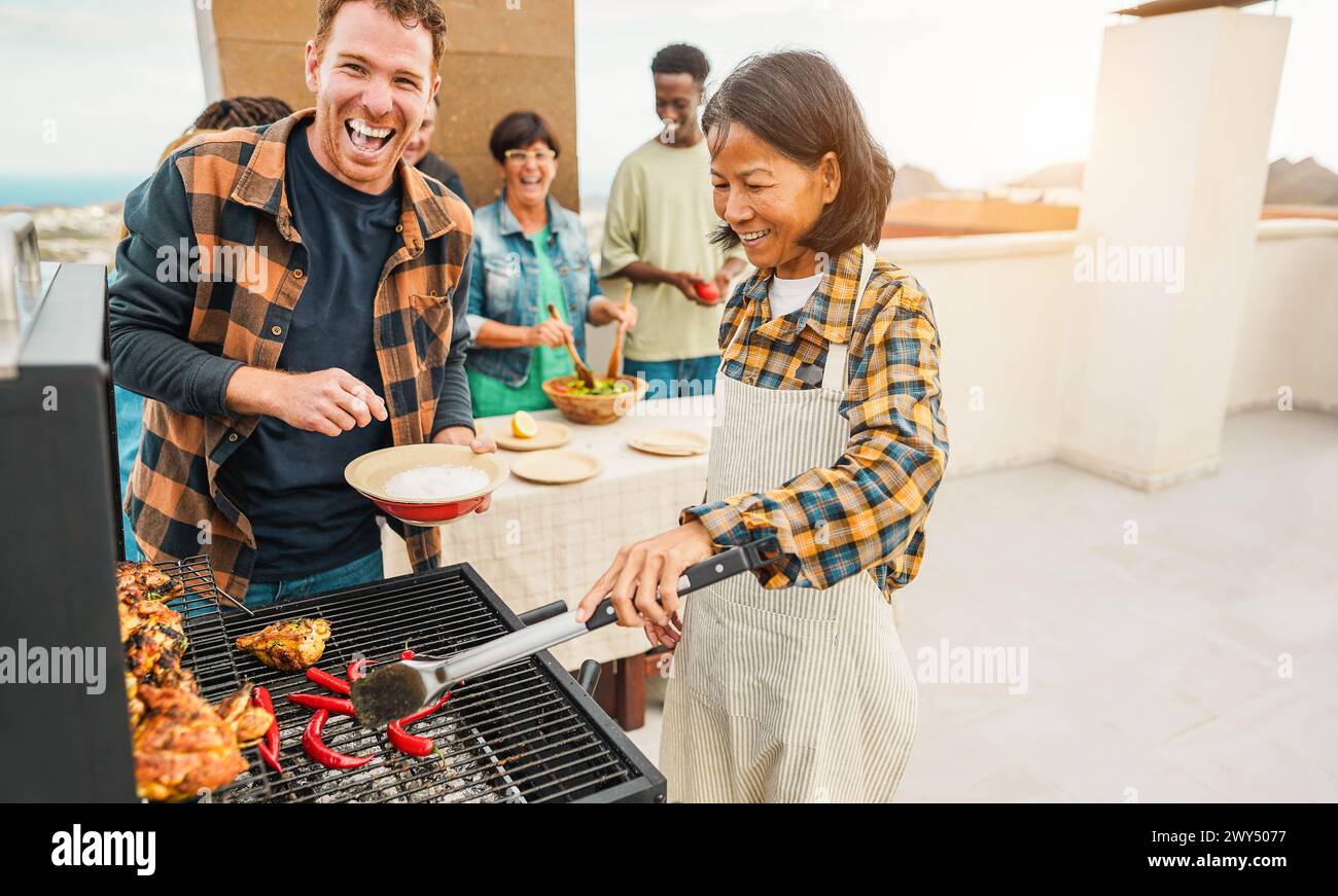 Happy multiracial friends having fun cooking healthy food with barbecue ...