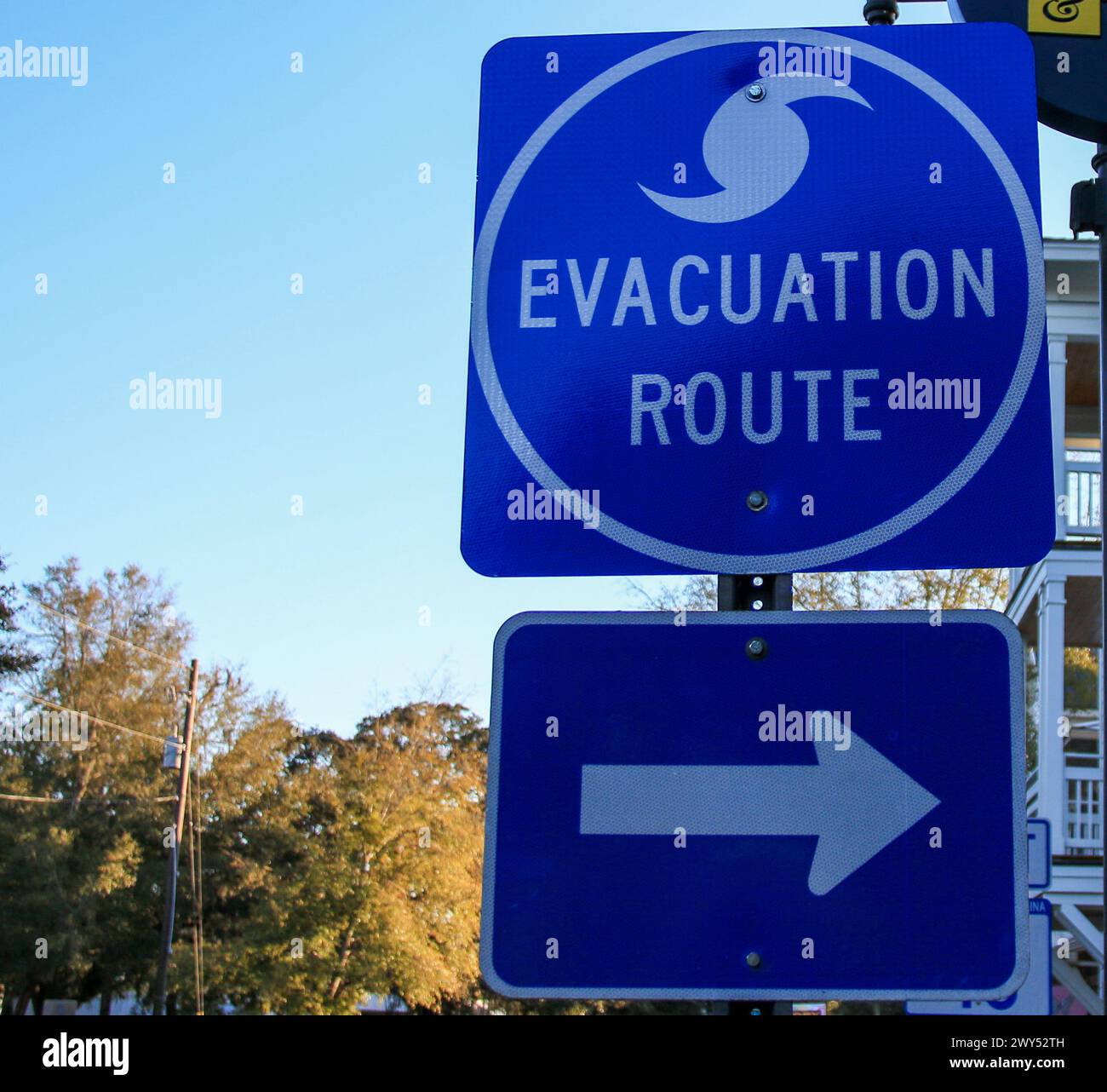 A blue street sign with white text indicating an evacuation route. The ...