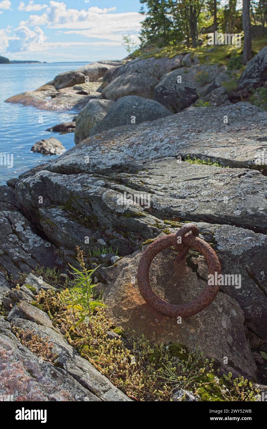 Old and rusty mooring ring fastened into a rock and used to tie up ...