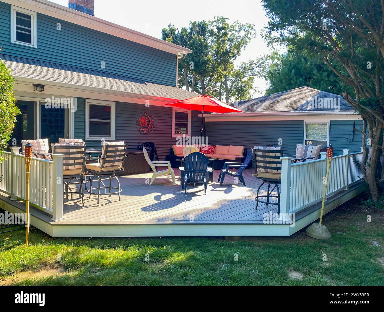 A deck set up with a table and chairs shaded by a large umbrella. The ...
