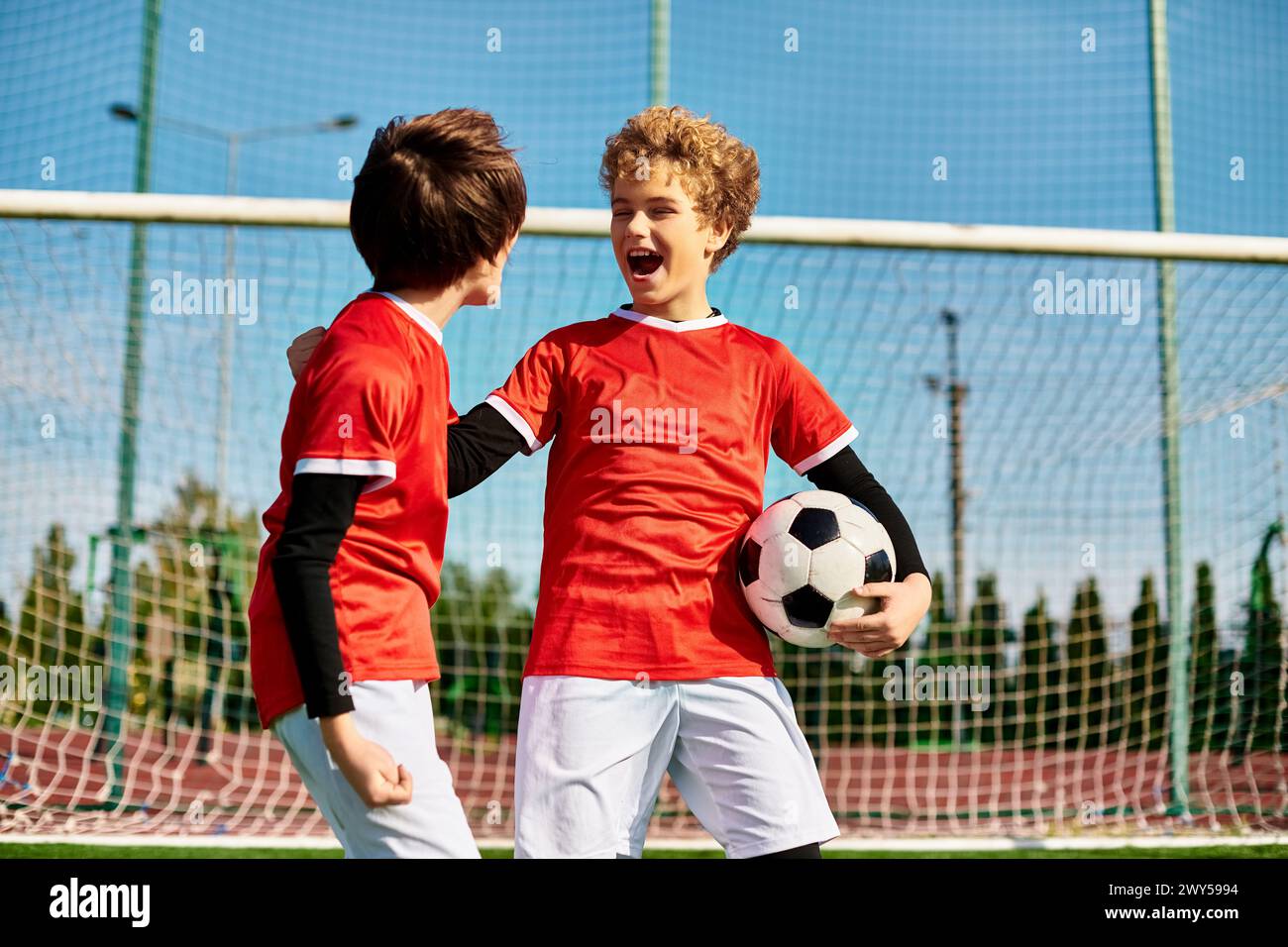 Two young men in athletic wear standing side by side on a soccer field ...