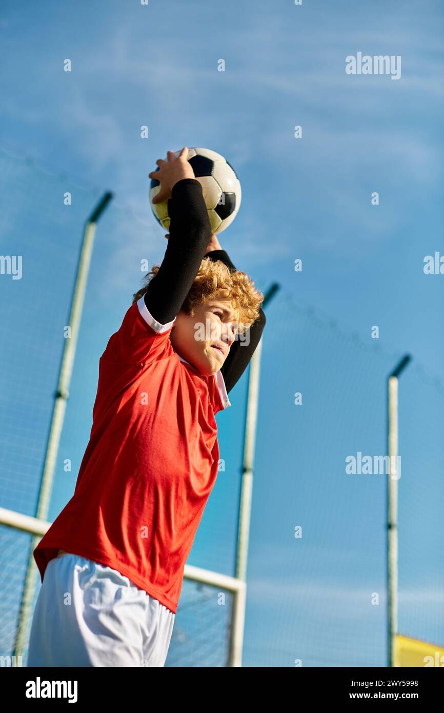 A youthful man joyfully lifts a soccer ball triumphantly into the sky ...