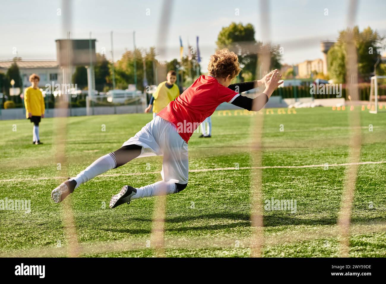 A young man, full of determination, kicks a soccer ball across a vast ...
