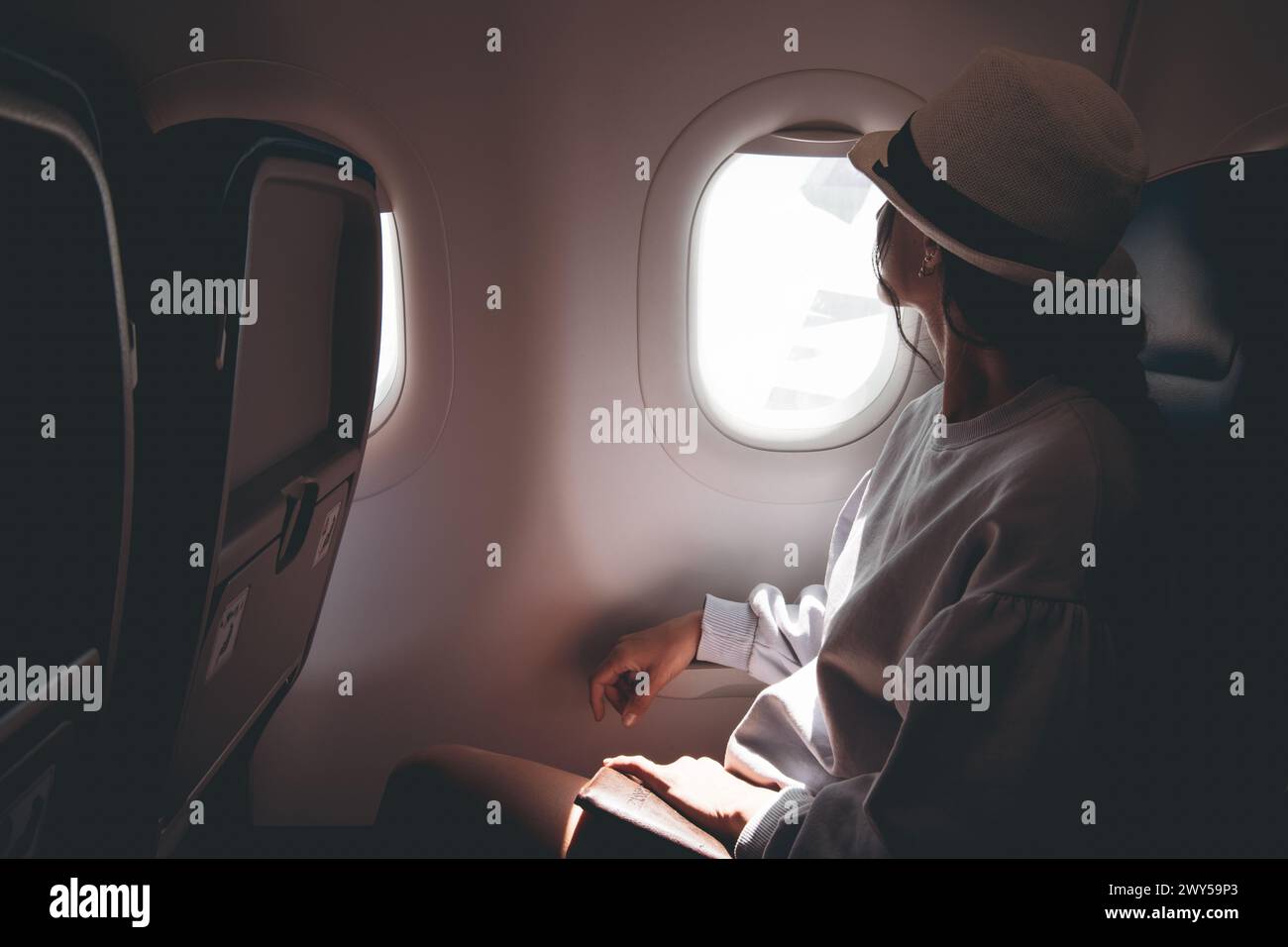 Woman looks out the window of an flying airplane. Young caucasian happy ...