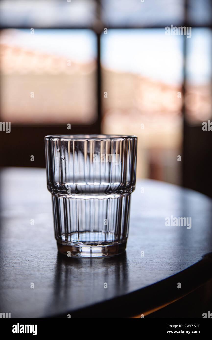Empty glass cup on a wooden table and in the background an open door ...