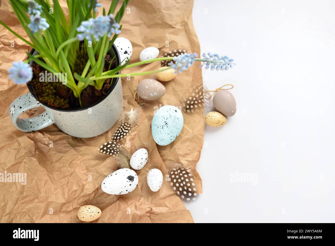 Easter eggs and light blue muscari flowers in cup on a white table ...