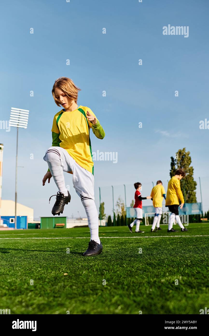 A young boy is passionately kicking a soccer ball on a green field. His ...
