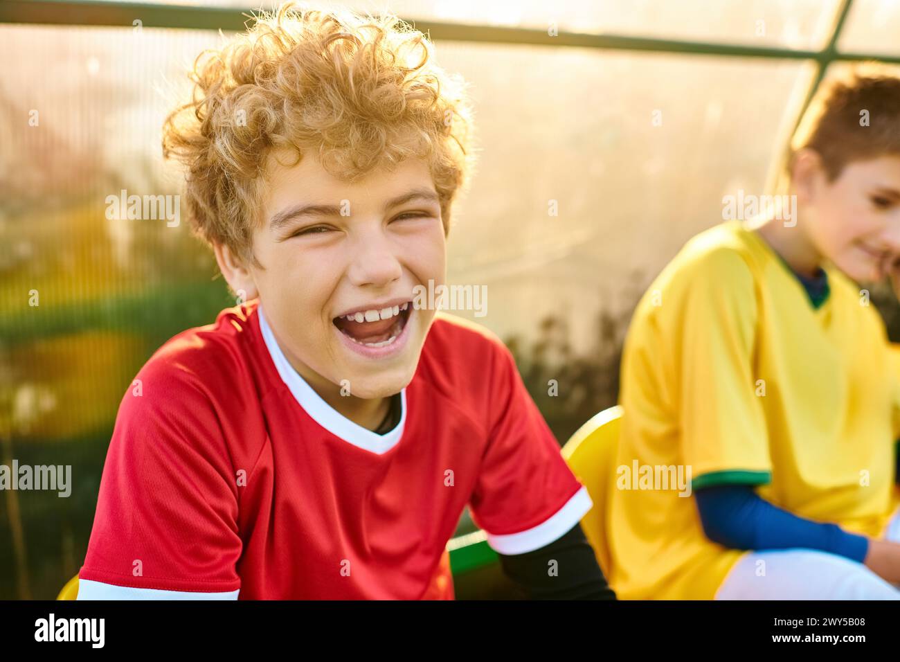 Two young boys sitting close together on a park bench, engrossed in ...