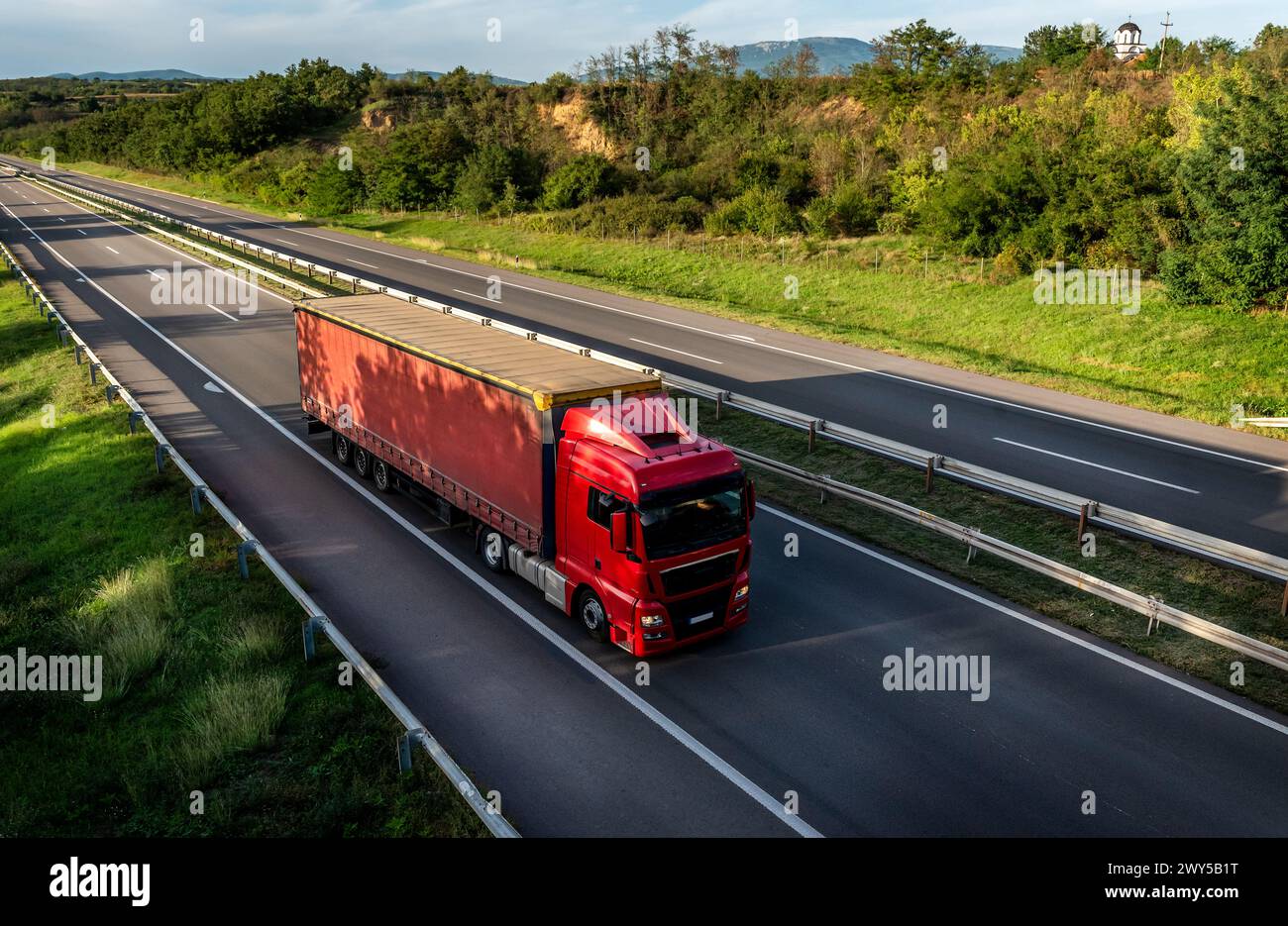 Highway scene with Red lorry truck with red trailer passing on a ...