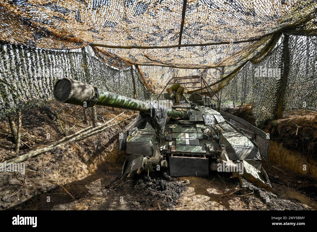 UKRAINE - MARCH 31, 2024 - Camouflage nets conceal a tank of the 1st ...