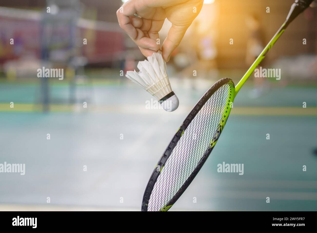 The badminton player holding a white shuttlecock and racket and ...
