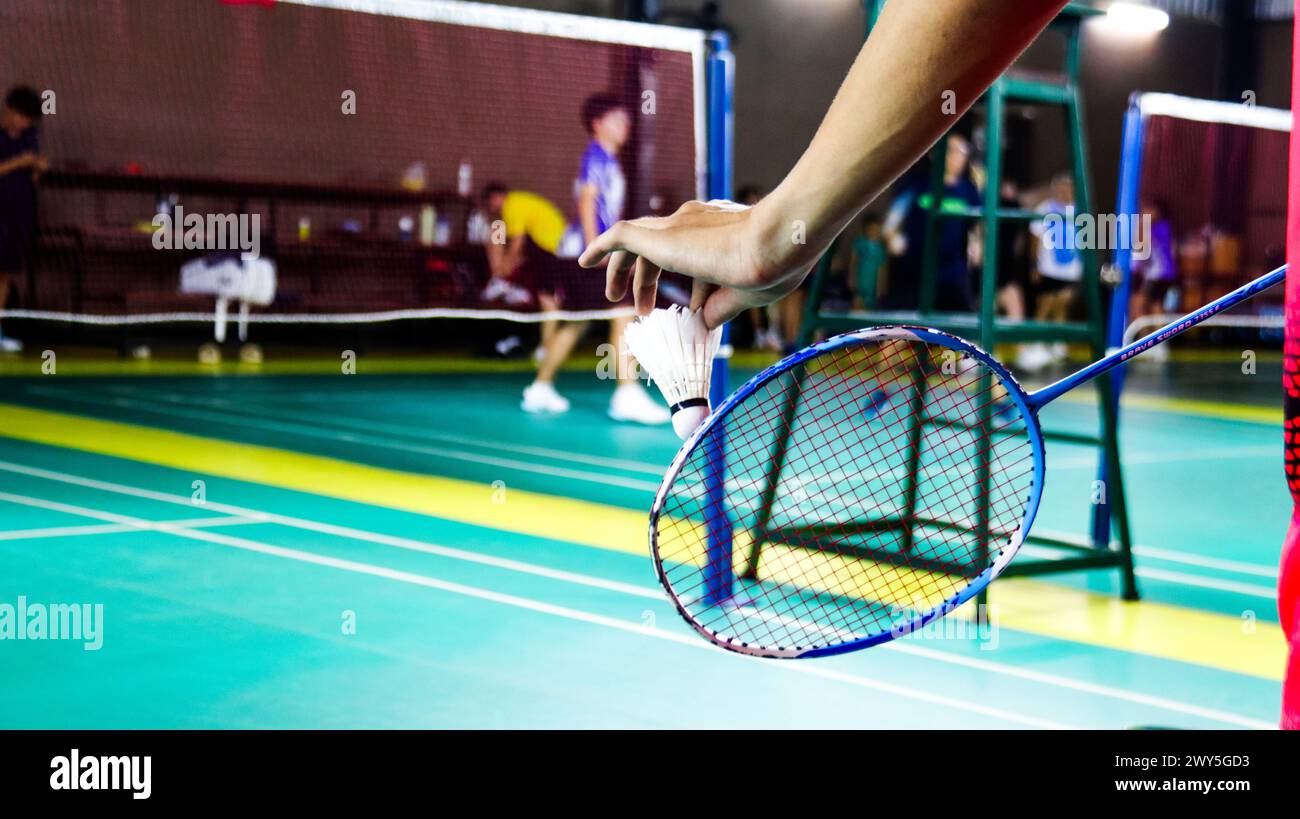 The badminton player holding a white shuttlecock and racket and ...