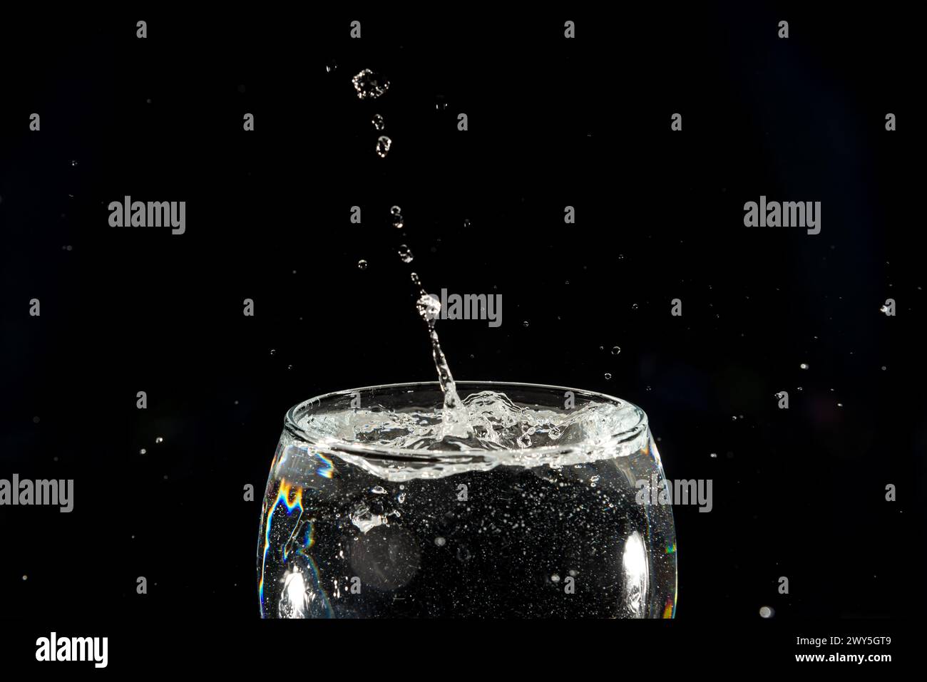 Close-up of a transparent glass cup with water inside and drops making ...