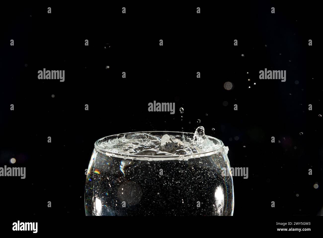 Splashing water drops in a full glass goblet. Splash Effect. Isolated ...