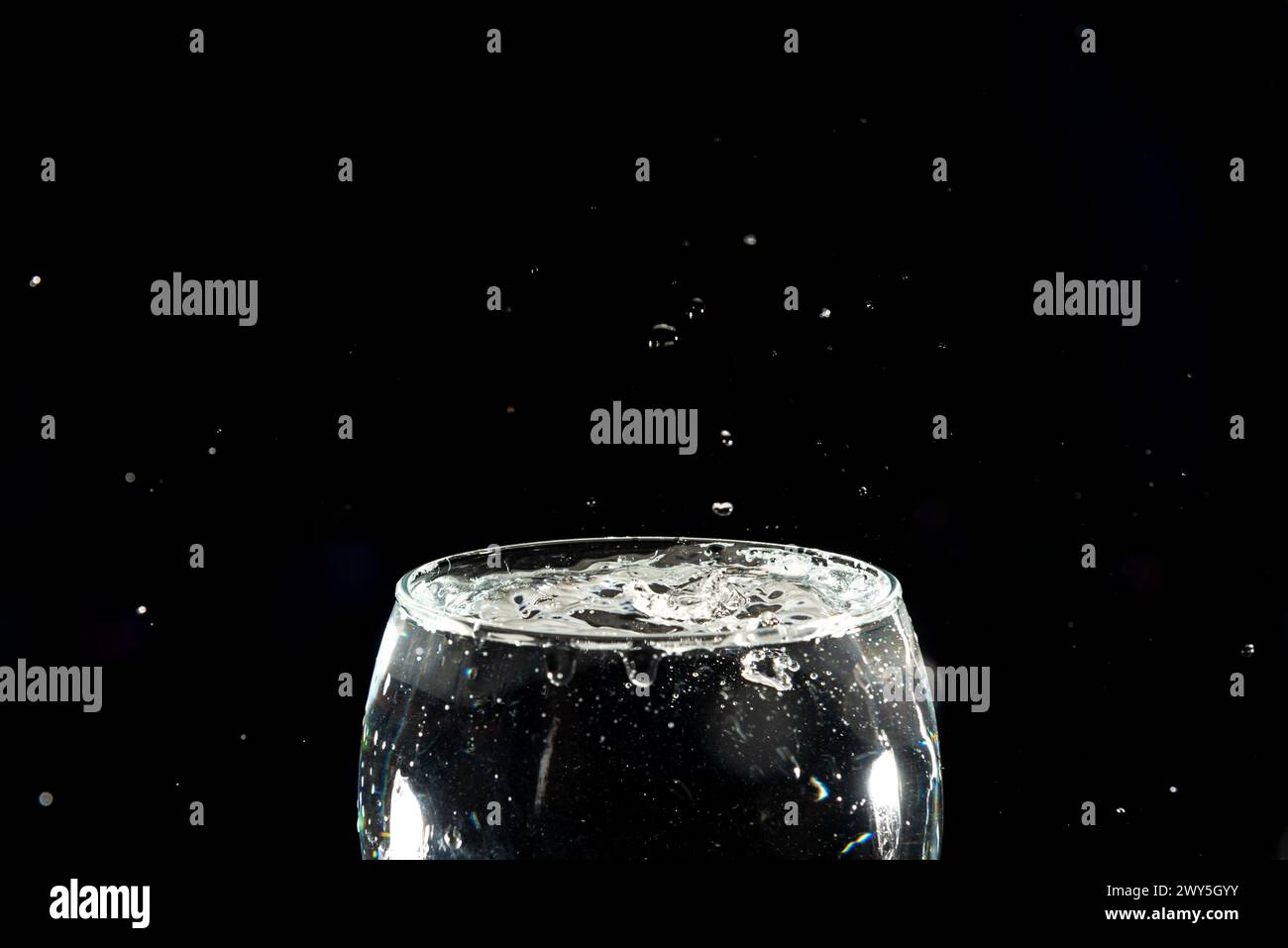 Splashing water drops in a full glass goblet. Splash Effect. Isolated ...