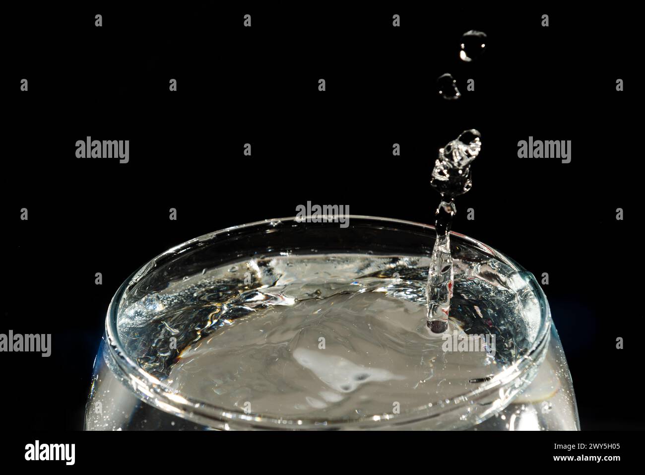 Close-up of a transparent glass cup with water inside and drops making ...