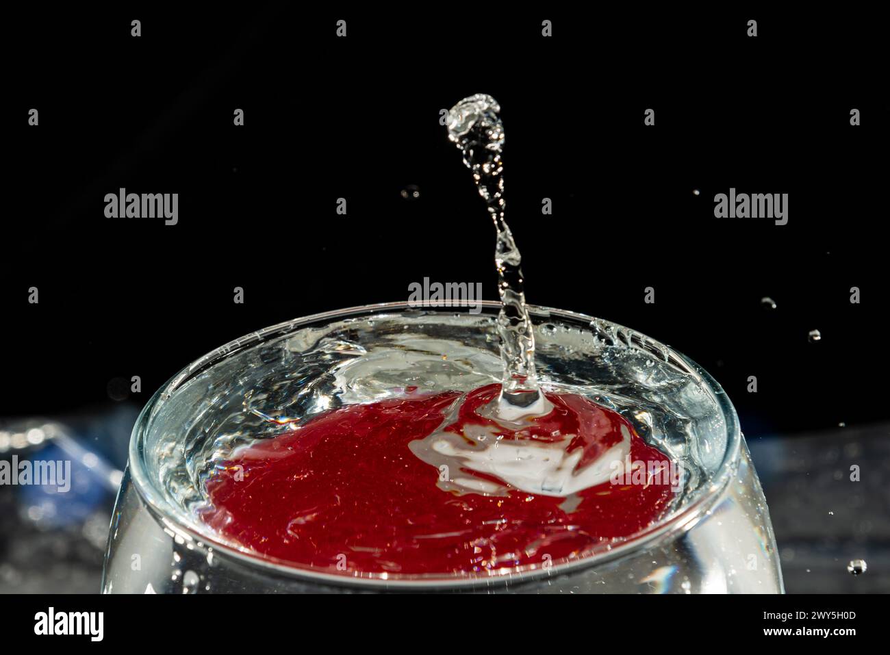Transparent glass bowl, filled with water, with red reflection and ...