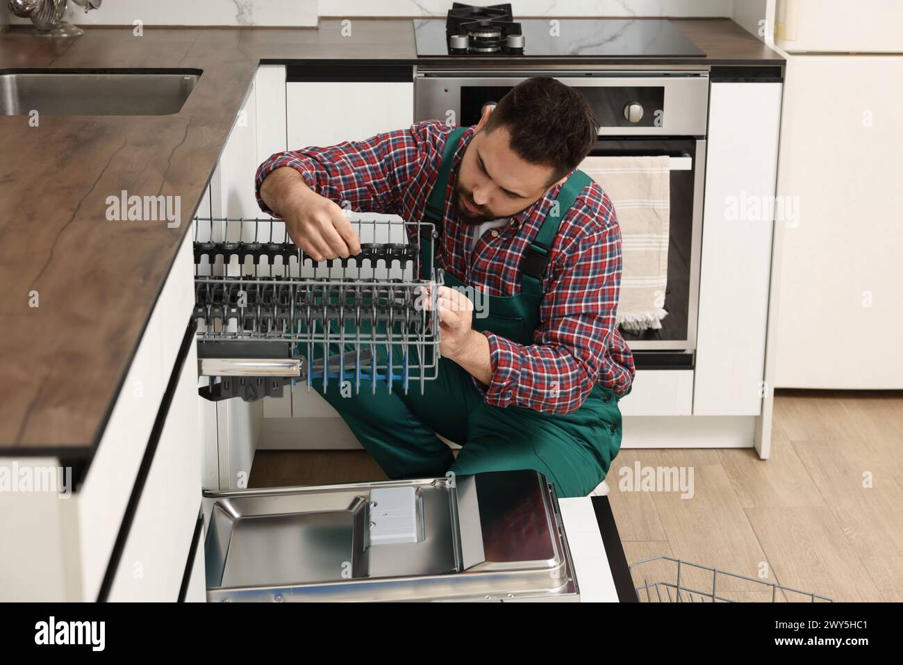 Serviceman repairing dishwasher cutlery rack in kitchen Stock Photo - Alamy