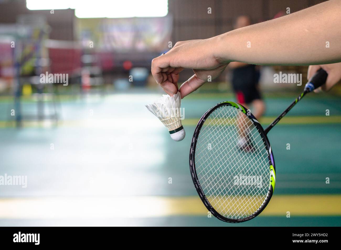 The badminton player holding a white shuttlecock and racket and ...