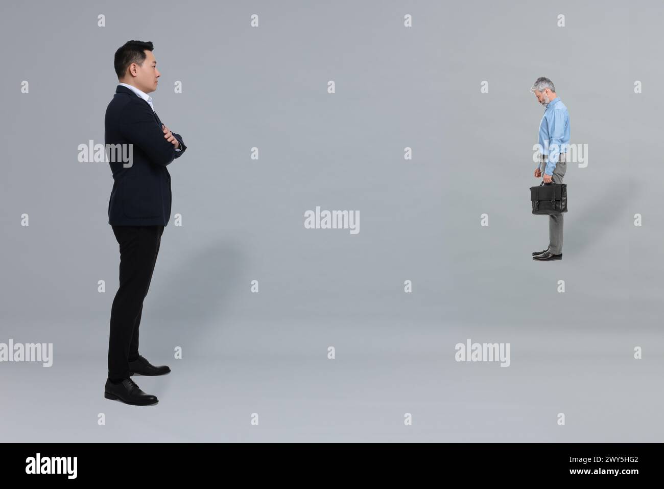 Giant boss and sad small man on grey background Stock Photo - Alamy