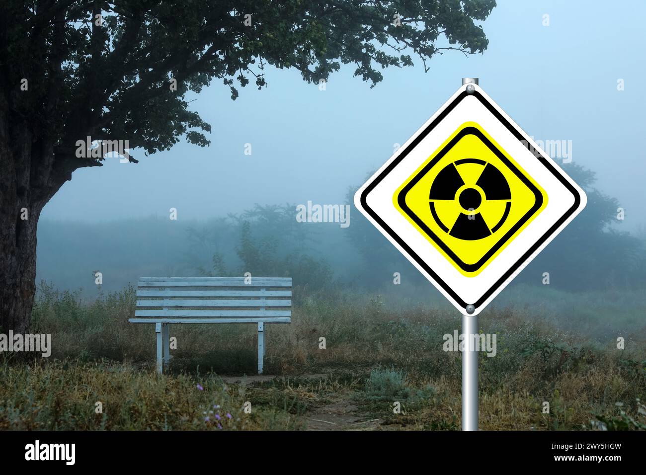 Radioactive pollution. Yellow warning sign with hazard symbol in rural ...