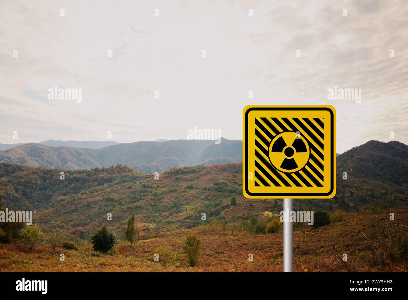 Radioactive pollution. Yellow warning sign with hazard symbol in rural ...
