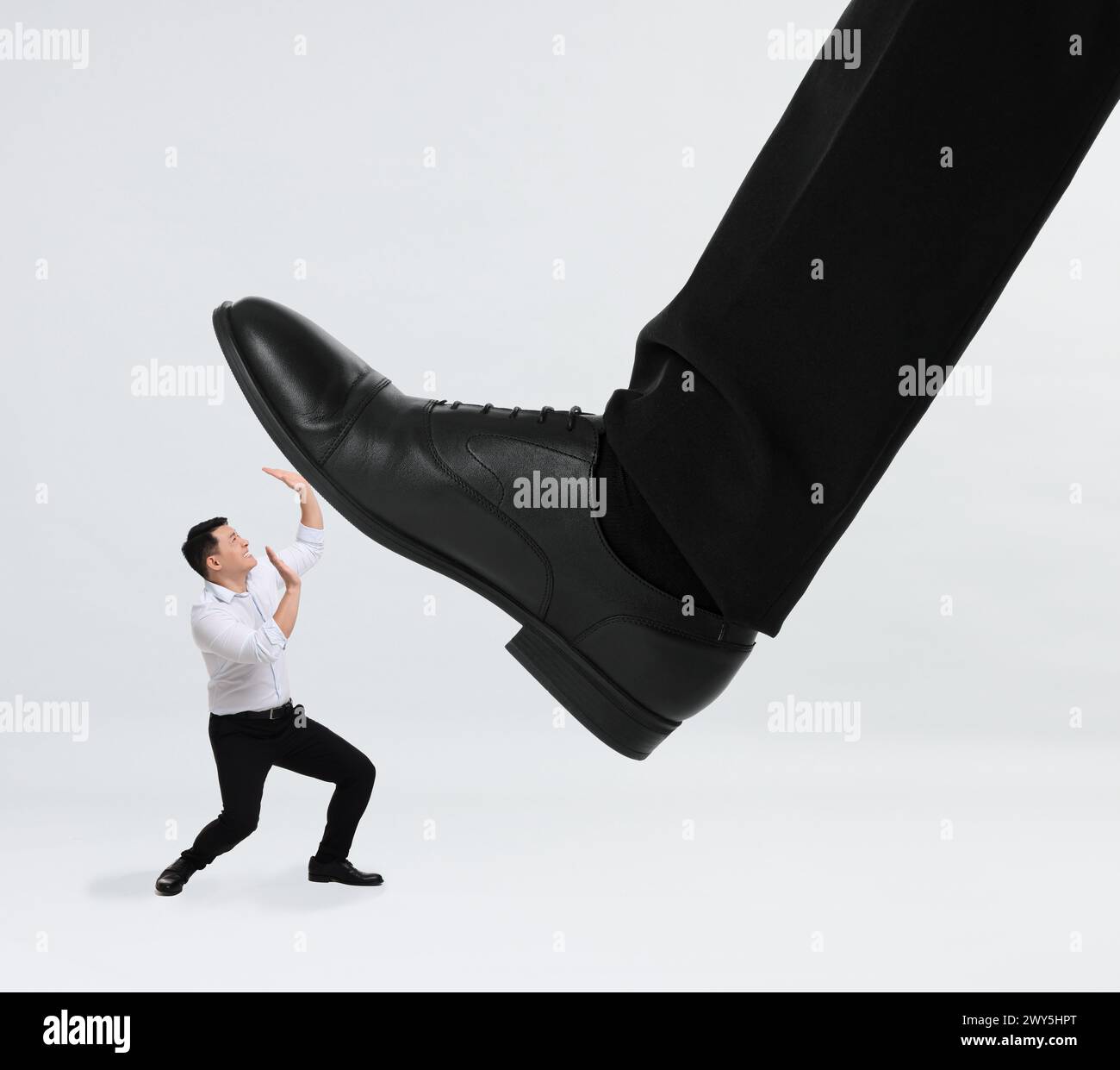 Giant stepping onto small man on white background Stock Photo - Alamy