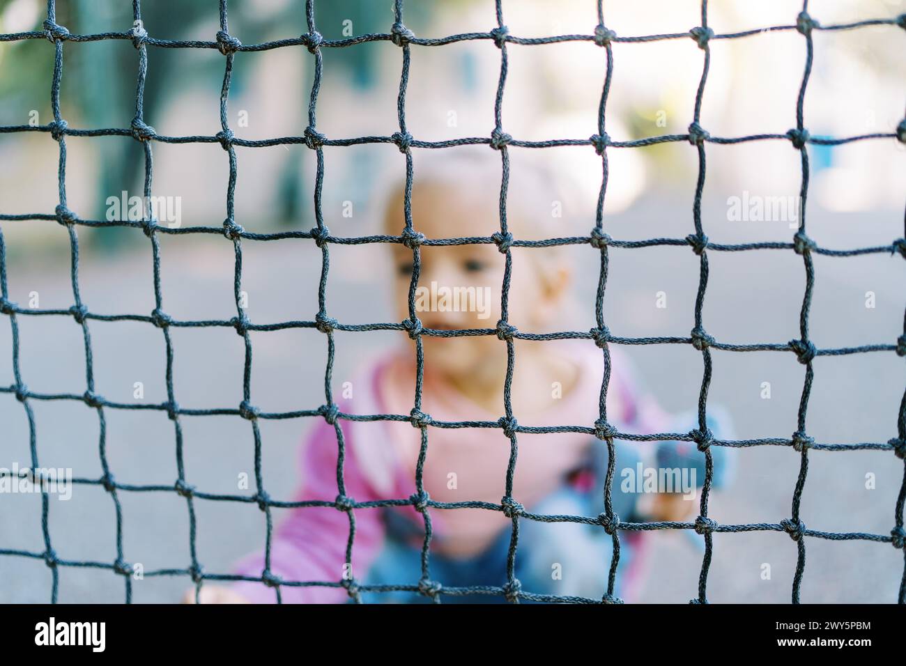 Little girl with a toy sat down behind the net. Blur Stock Photo - Alamy