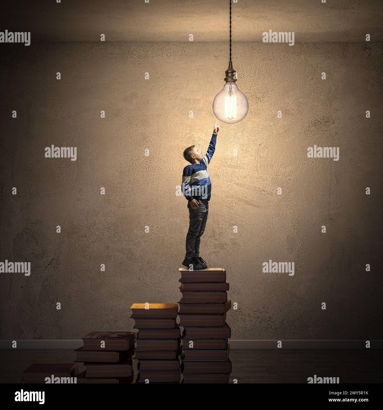 boy climbs a ladder of books and reaches for a light bulb, a concept of ...