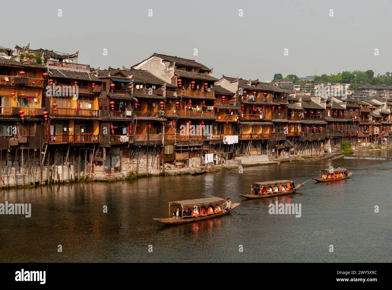 Tourist boats pass the old wooden buildings on the edge of the river in ...