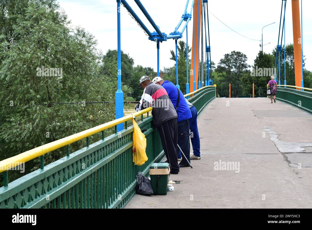 Fishermen catch fish on float rods standing on the bridge leaning on ...