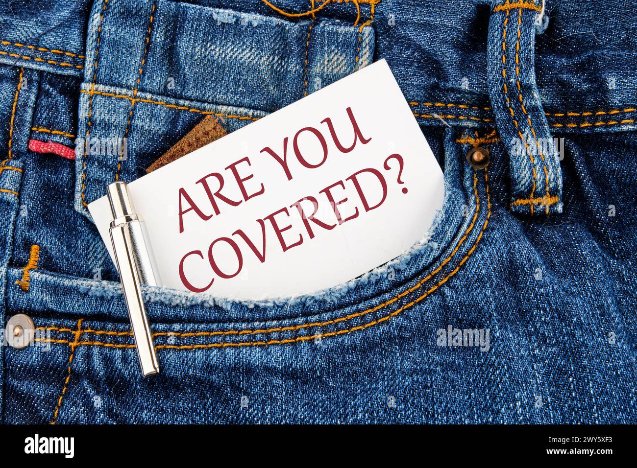 ARE YOU COVERED text written on a business card peeking out of a jeans ...