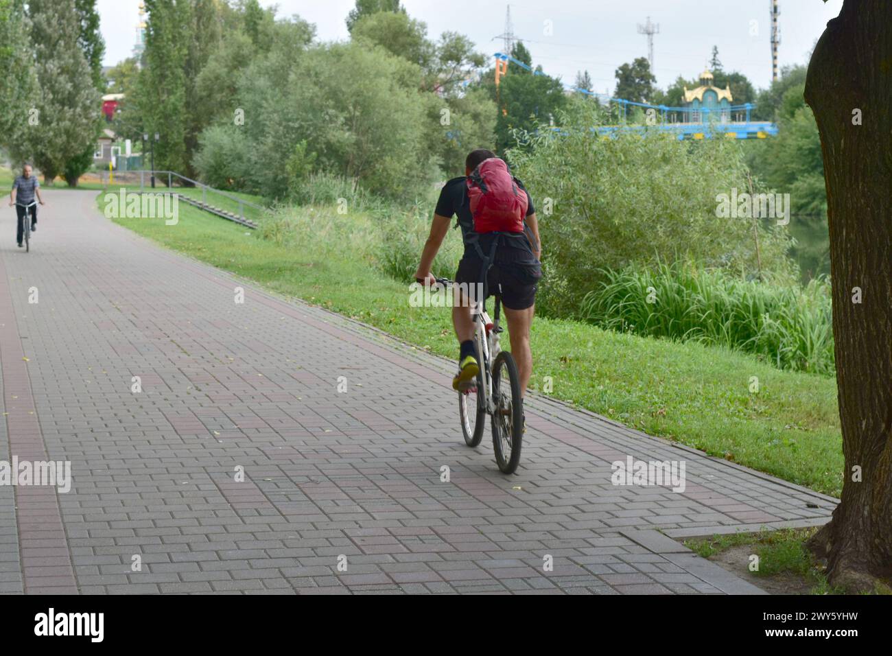 The photo shows a young athlete riding a bicycle along a park track ...