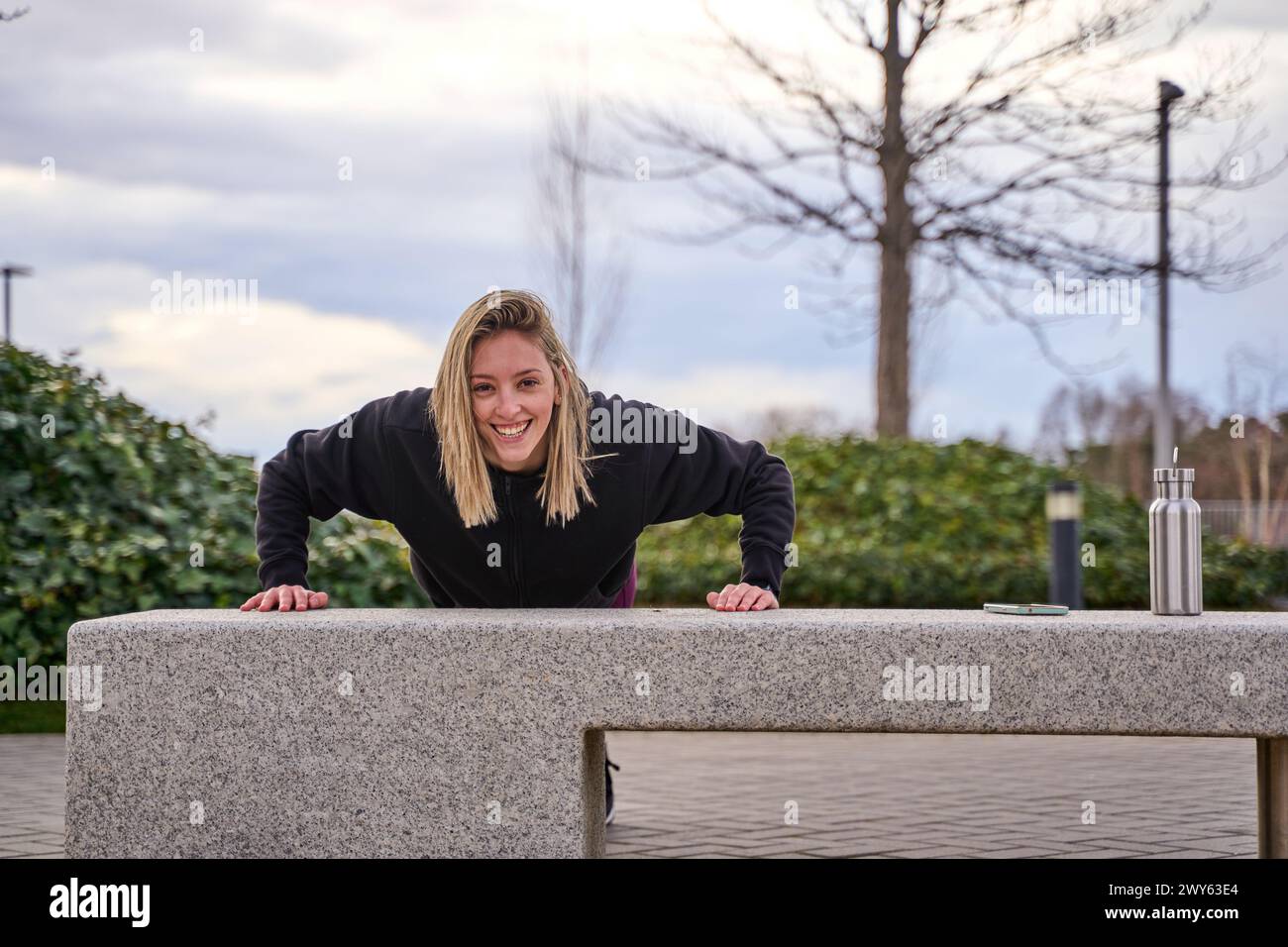young woman doing bicep push-ups on a street bench in the street Stock ...